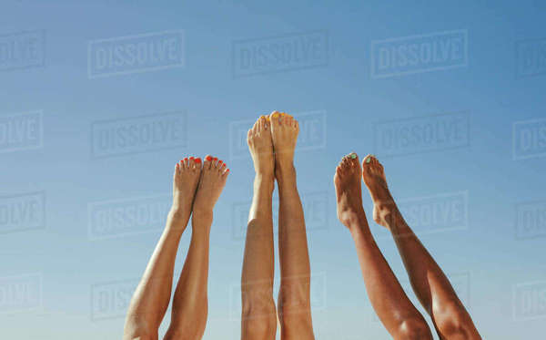 Close up of three pair of legs of young women raised up pointing to the ...