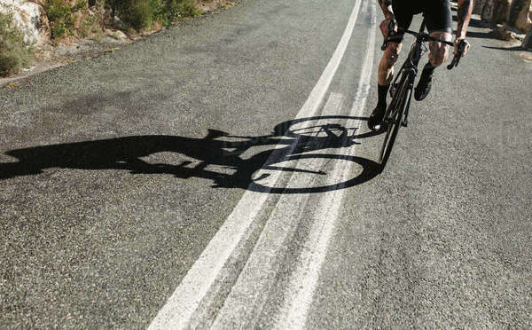 Male bicycle rider putting effort while climbing up the mountain ...
