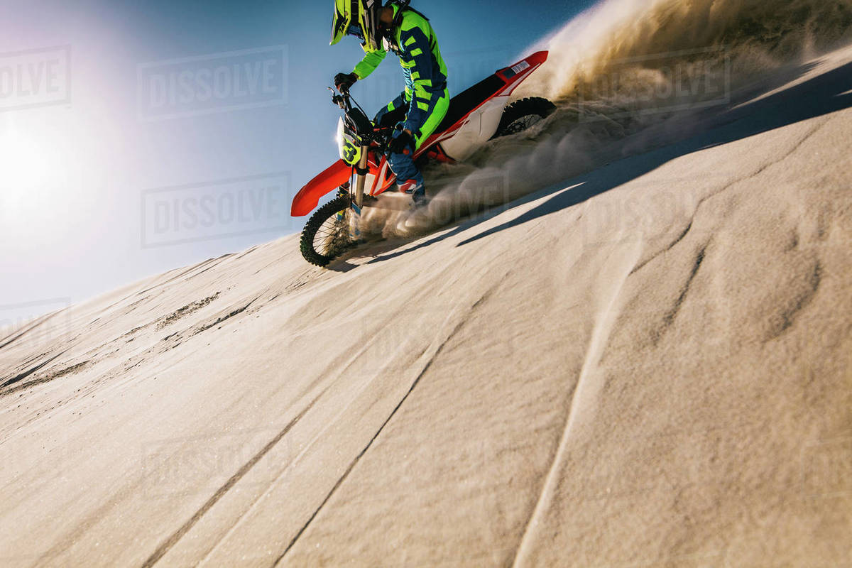 Professional motorbike rider taking a turn while riding on the sand ...