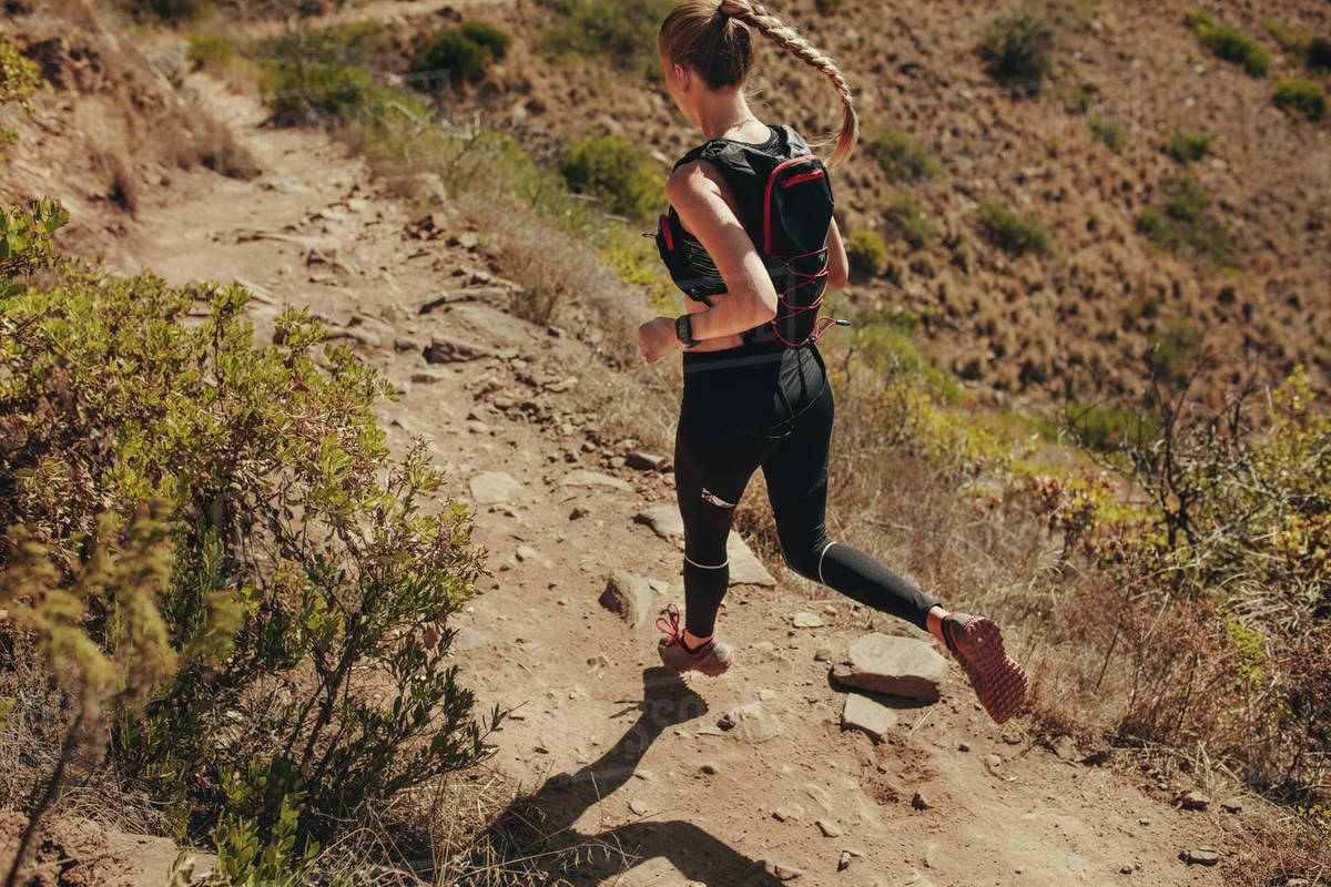 Top view of young woman running on mountain trail. Woman running on ...