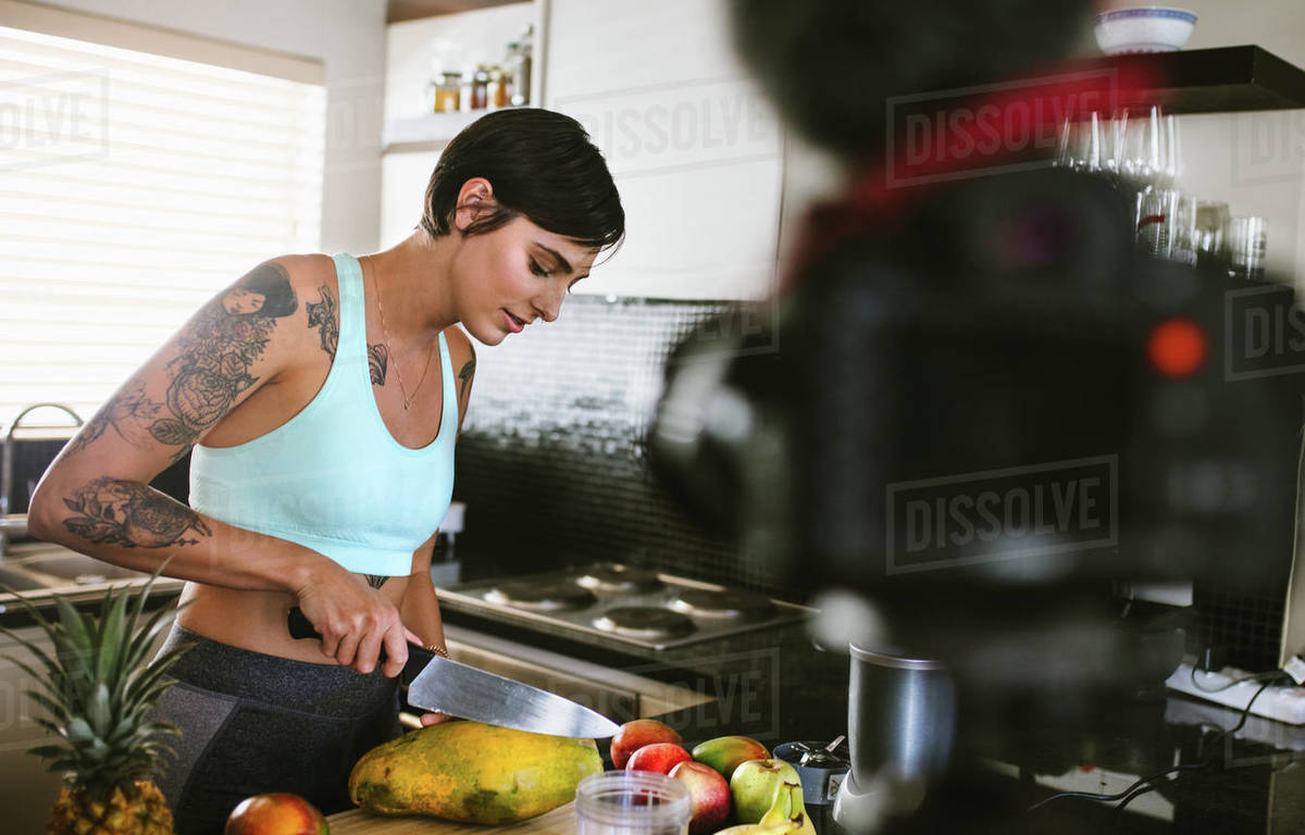 Young woman in kitchen recording video on camera. Female working on ...