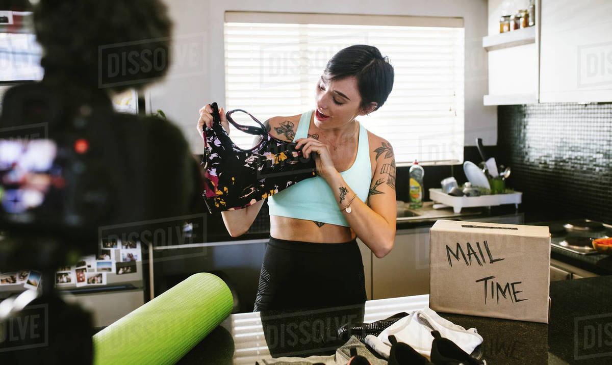Happy female social media influencer reviewing sports bra on camera ...