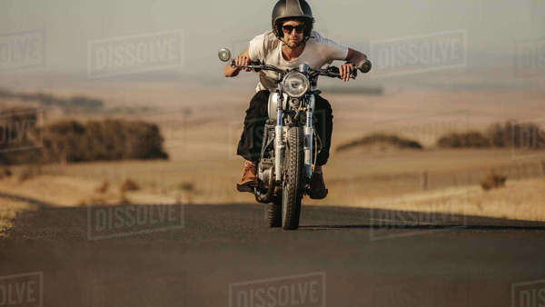 Portrait of young man driving a motor bike fast on country highway ...
