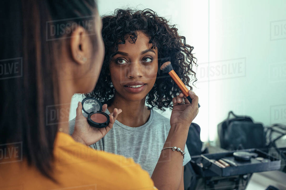 Makeup artist applying foundation to a model using a brush ...