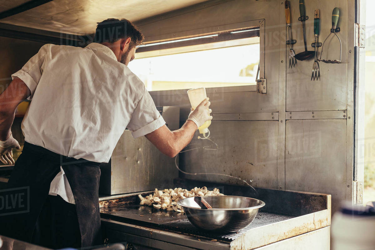 Young chef cooking some of his favorite dishes in a food truck. Man ...