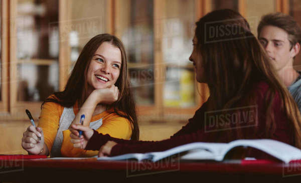 Smiling young woman sitting in the classroom and talking with ...