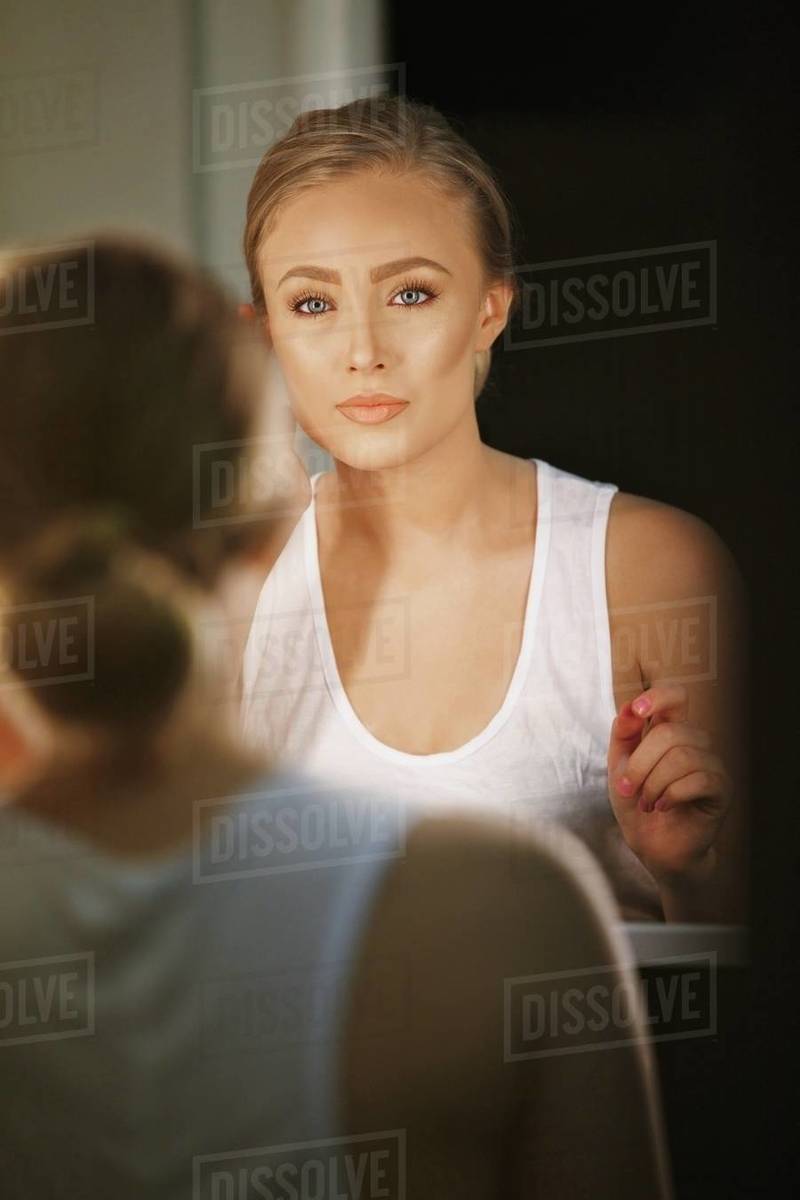 Attractive female fashion model in front of mirror getting ready before ...