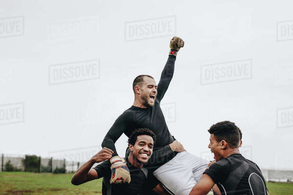 Teammates lifting goalkeeper on their shoulders and celebrating success ...