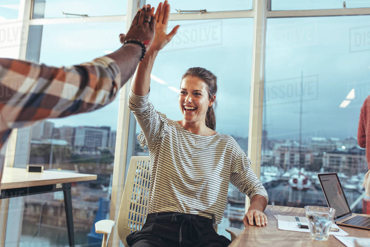 Business colleagues giving high five to each other in office. Team ...