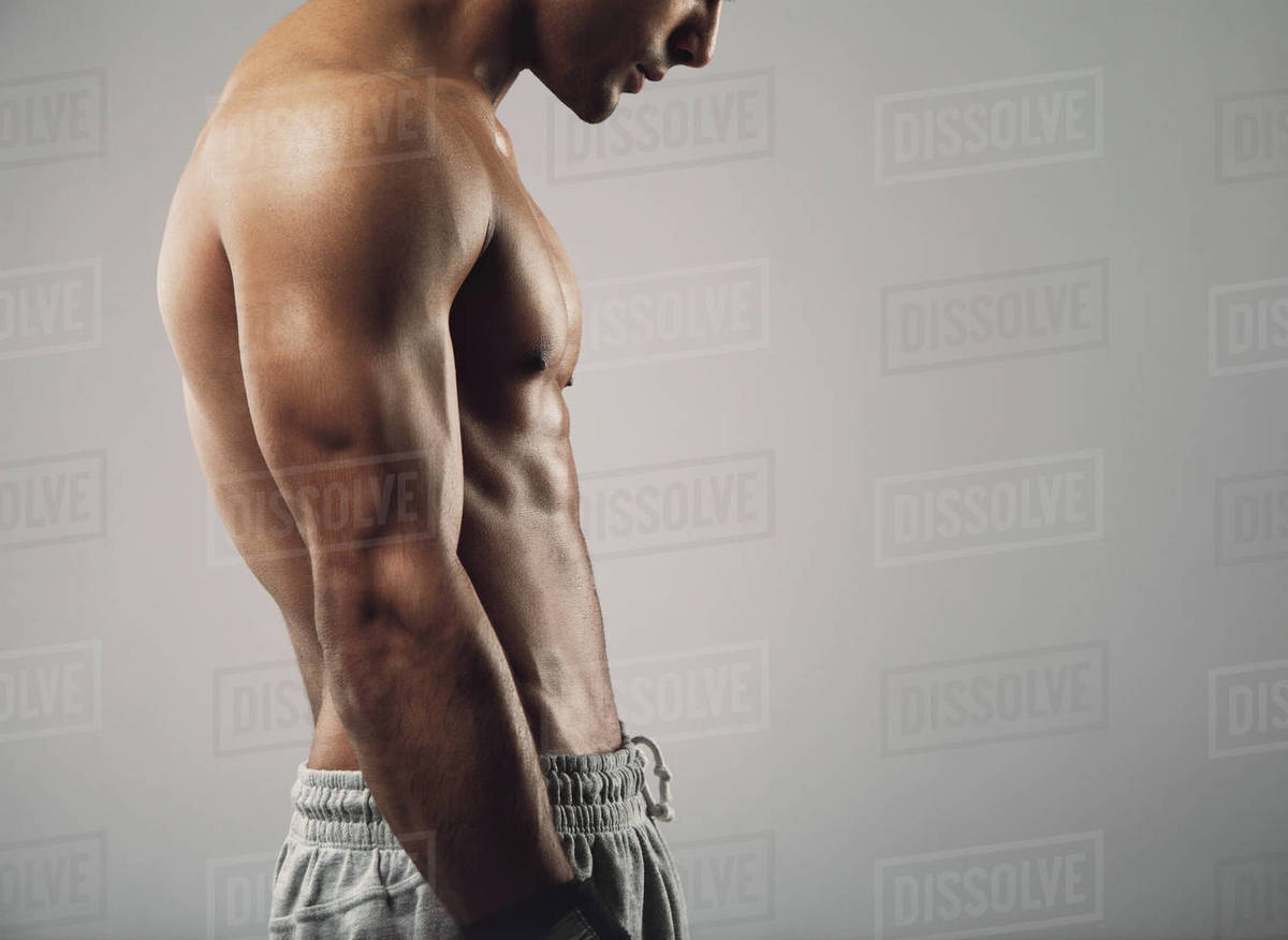 Cropped image of muscular young man torso on grey background with copy ...