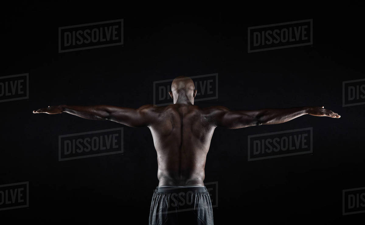 Portrait of a strong back of a black muscular man stretching his arms ...
