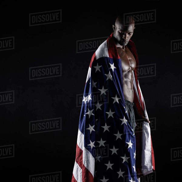 Male athlete carrying an American flag against black background. Studio ...