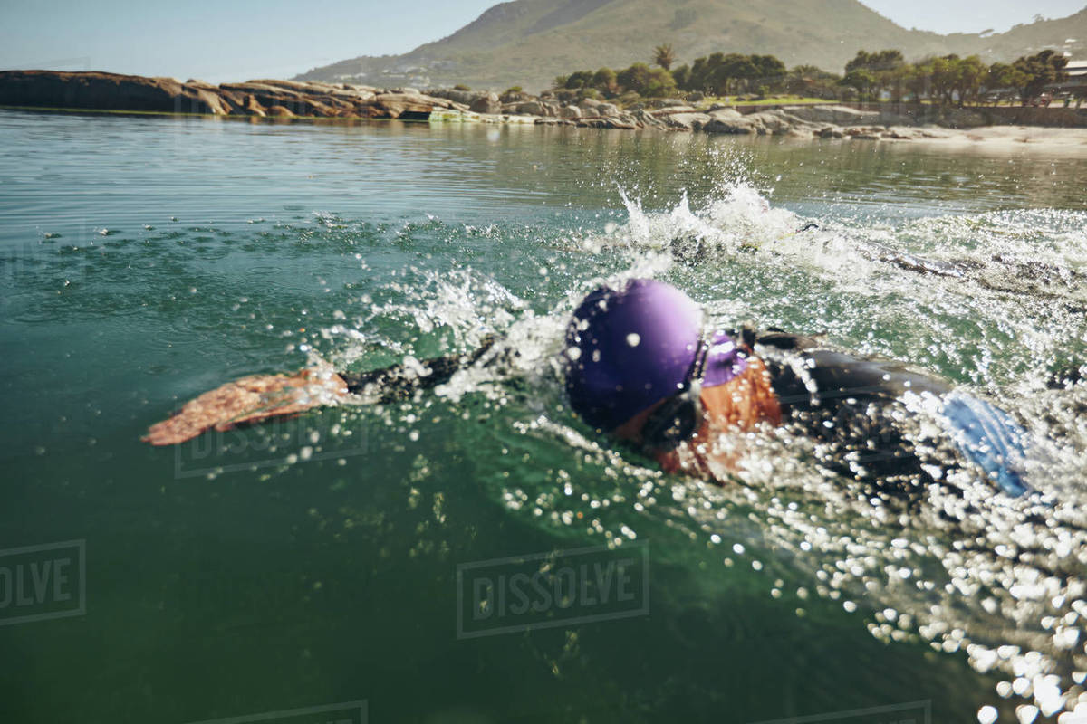 Male competitor swims freestyle in the water. Male athlete swimming on ...