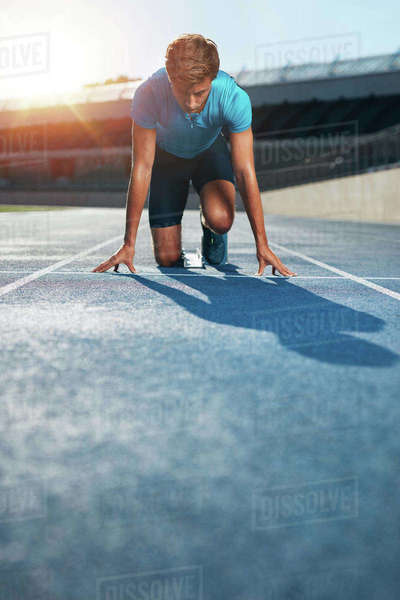 Professional male track athlete in set position on sprinting blocks of ...