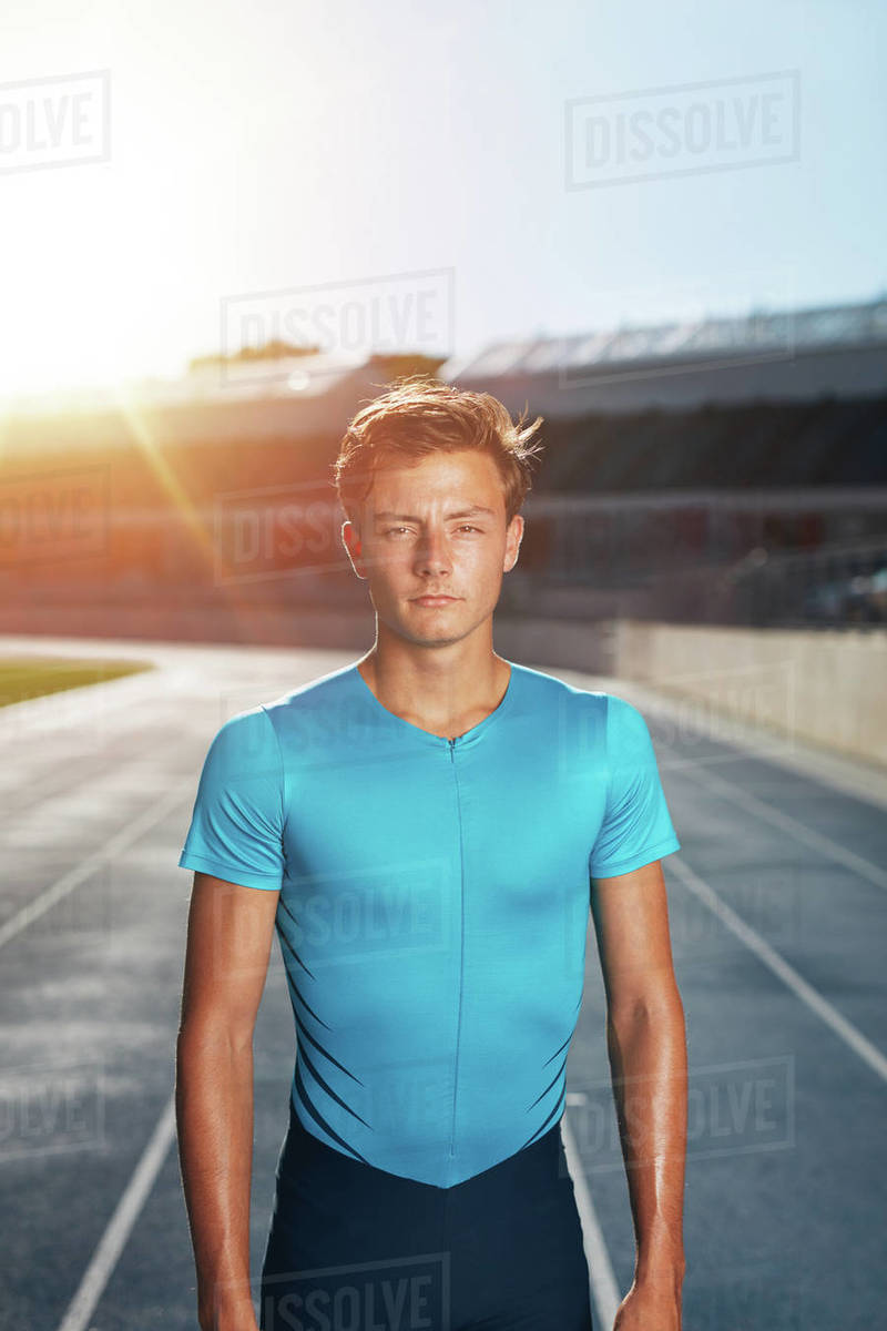 Young man after run standing on outdoor stadium race track. Fit male ...
