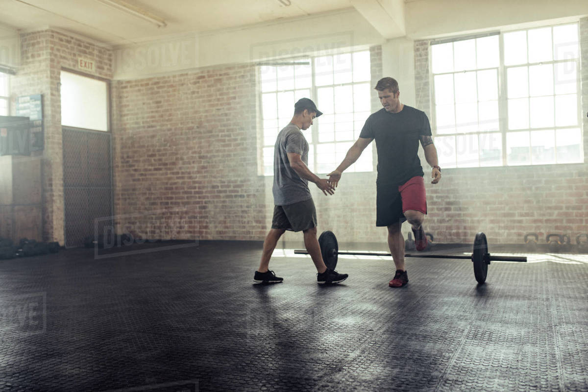 Young man with personal trainer preparing for a heavy weight training ...