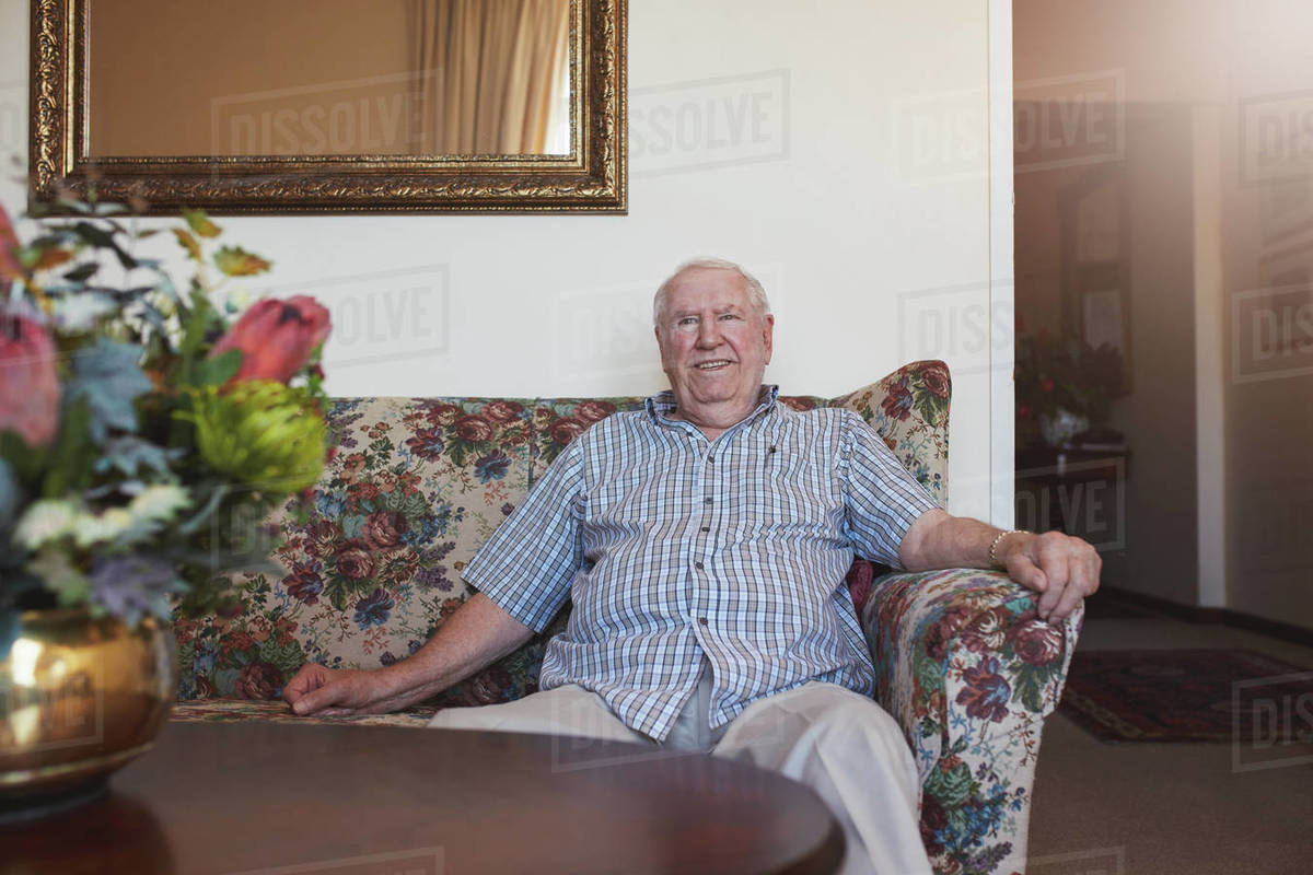 Indoor shot of happy senior man sitting relaxed on a couch at old age ...