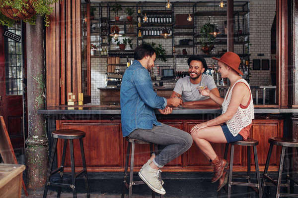 Group of young friends sitting and talking at a cafe. Young men and ...