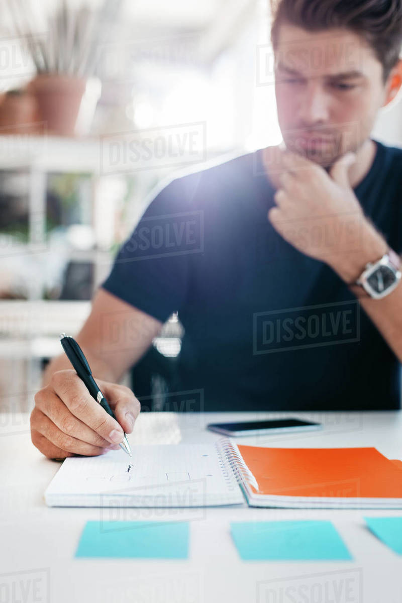 Businessman writing down some important notes in office diary at his ...