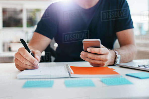 Close up shot of a man taking down note in a personal organizer with ...