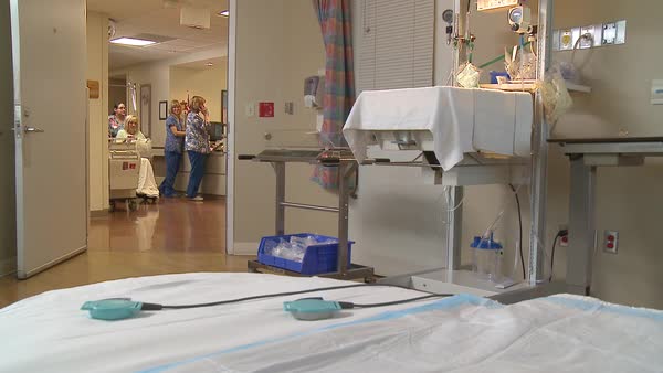 Nurse pushing a pregnant woman in a wheelchair into an operating room ...