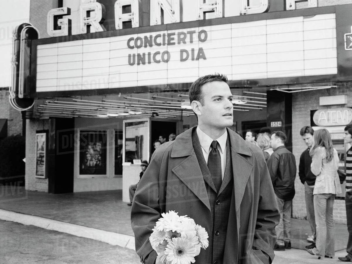 Man in suit with flowers waiting in front of movie theater - Royalty ...