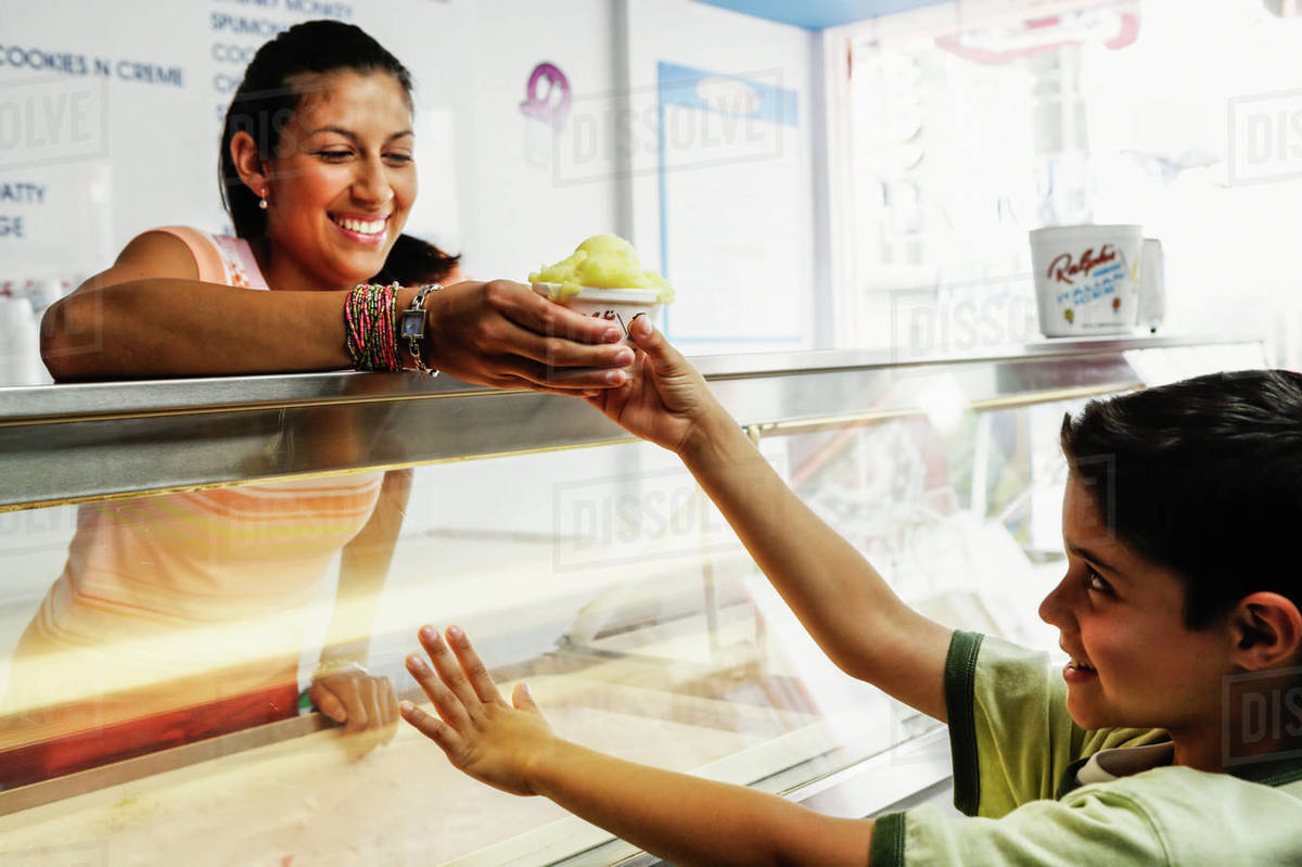 Teenage girl giving boy ice cream in shop - Stock Photo - Dissolve