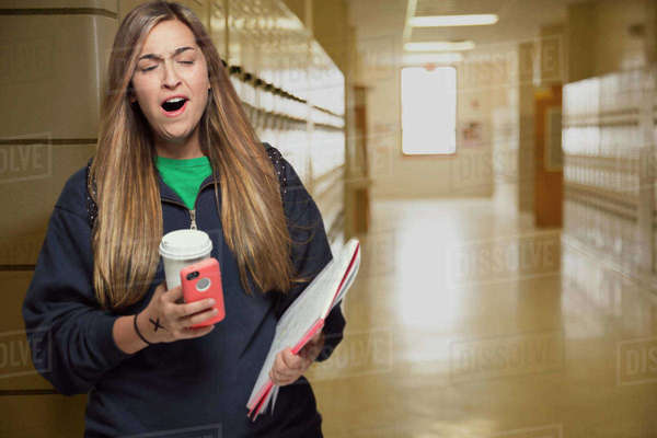Middle Eastern student yawning in college hallway - Stock Photo - Dissolve