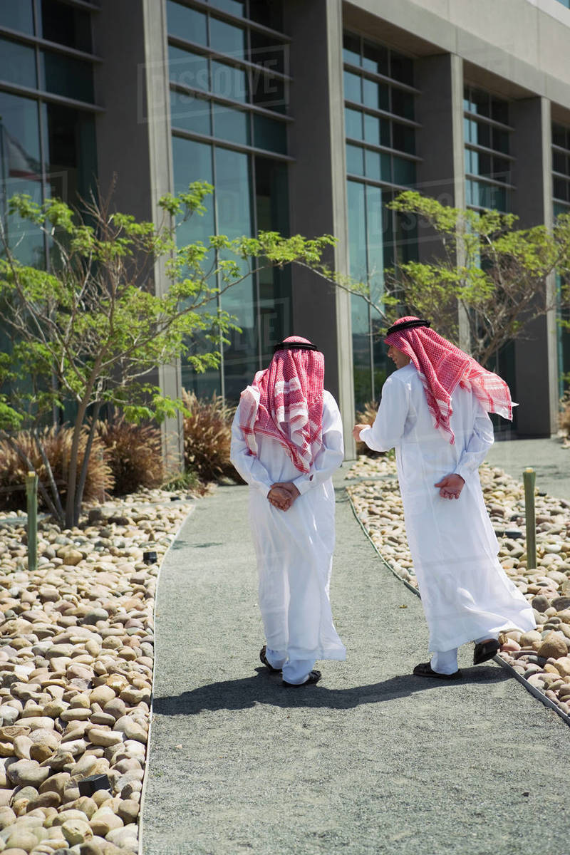 Middle Eastern men in traditional clothing walking on path - Stock ...