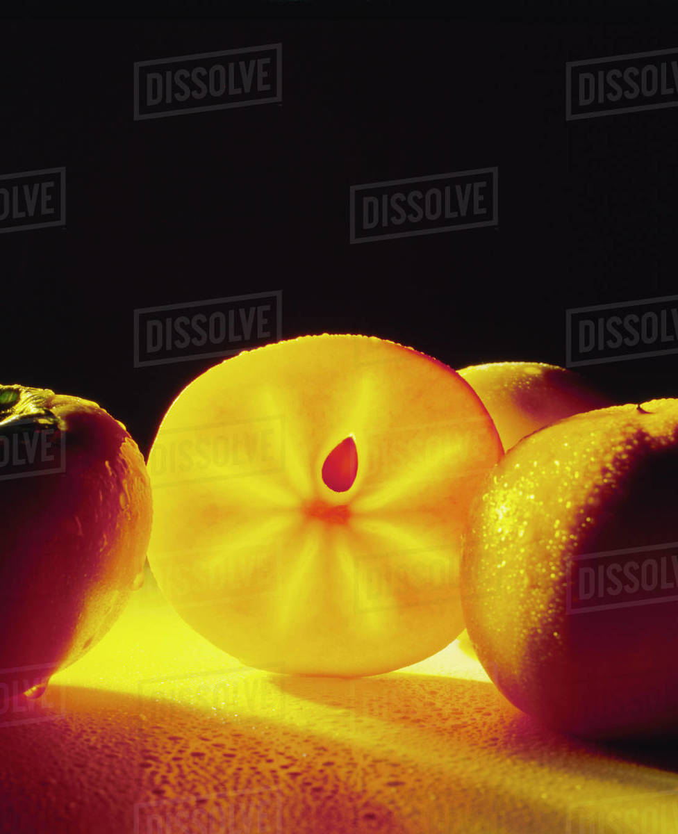 Backlit slice of Persimon surrounded by whole fruit - Royalty-free ...