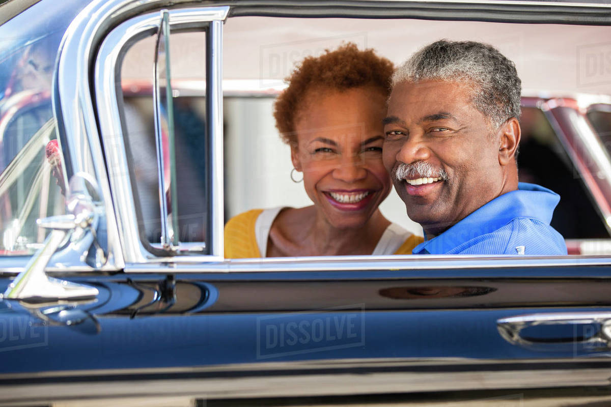 Older couple sitting in a classic car looking to camera smiling ...