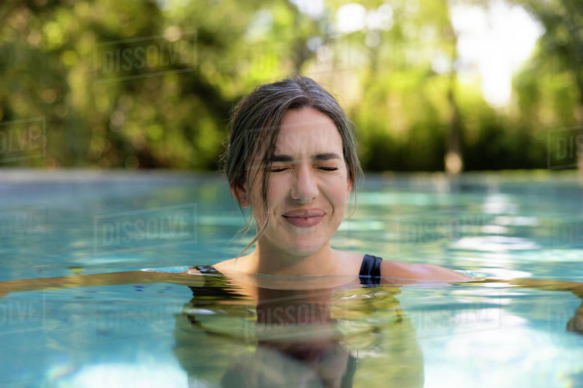 Portrait of caucasian woman floating in swimming pool in backyard ...