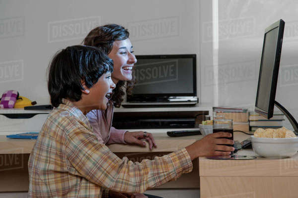 Young siblings watching a movie on a computer laughing. - Royalty-free ...