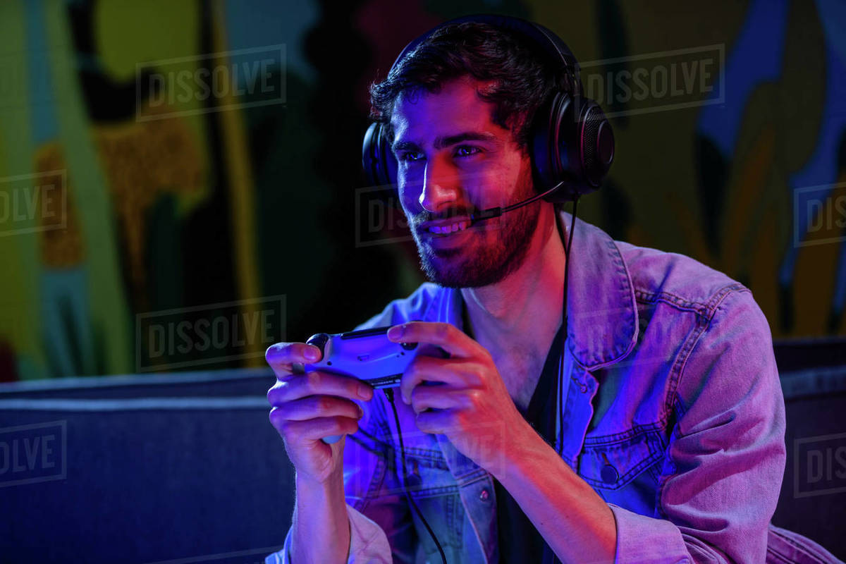 Video game streamer in his room with colored lights and game controller ...