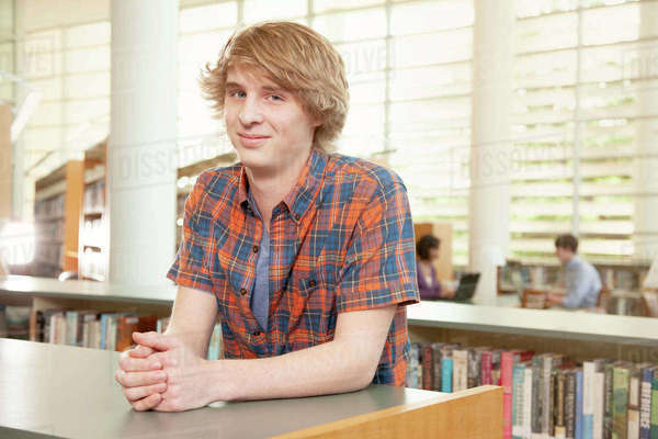 Portrait of college male in library looking at camera smiling ...