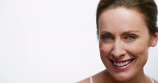 A woman looking down off camera, then looking into camera smiling ...