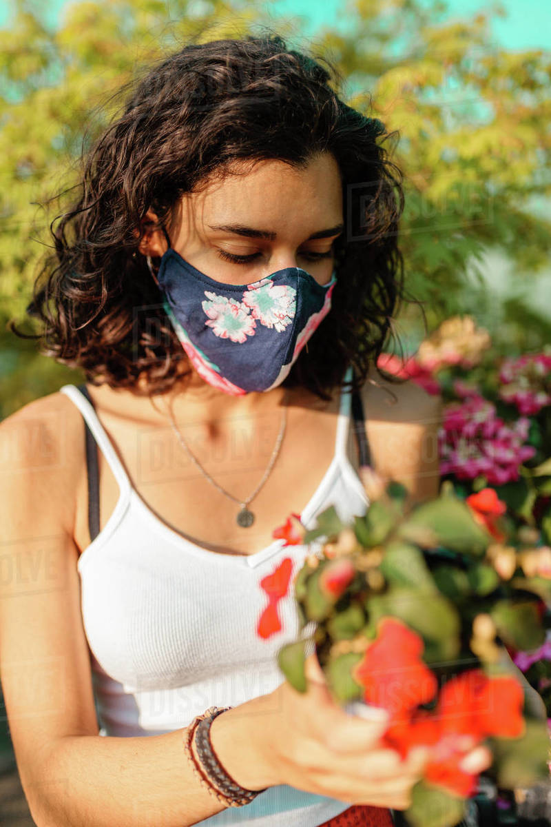 Woman with face mask gardening in greenhouse. People outdoor activities ...