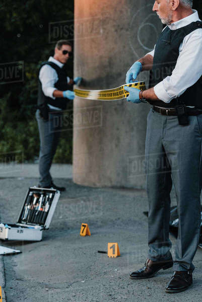 middle aged male police officers in latex gloves setting police line at ...