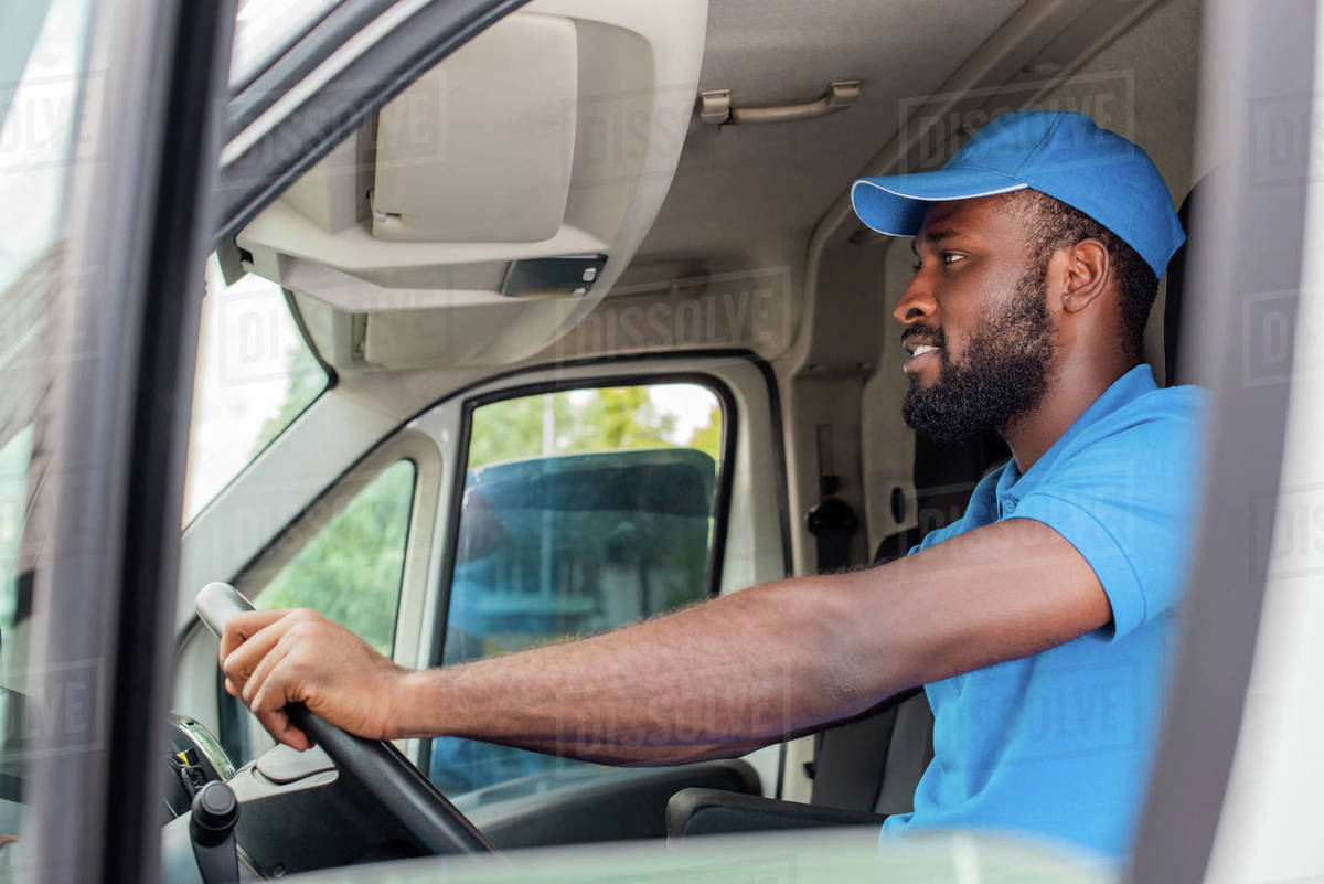 side view of african american delivery man driving van - Royalty-free ...
