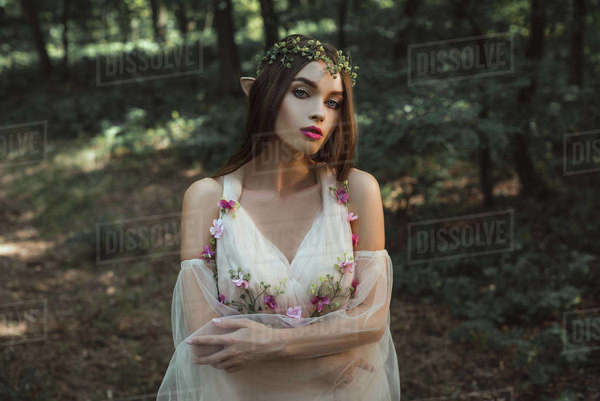 Attractive female elf in dress and floral wreath in forest - Stock ...