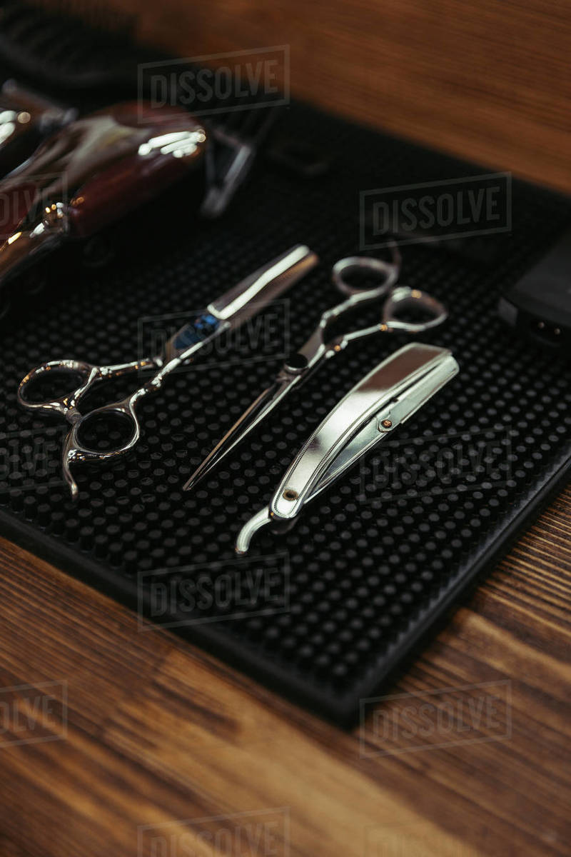 Close-up view of professional scissors and straight razor on wooden ...