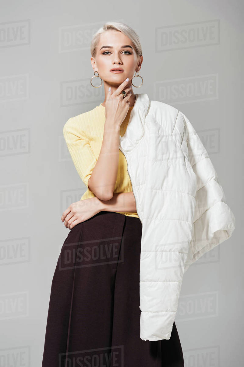 Stylish female model posing with jacket over shoulder isolated on grey ...