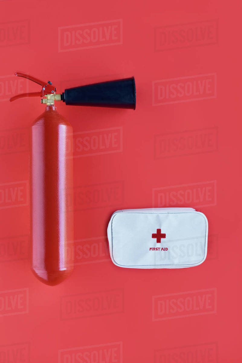 top view of fire extinguisher and first aid kit isolated on red ...