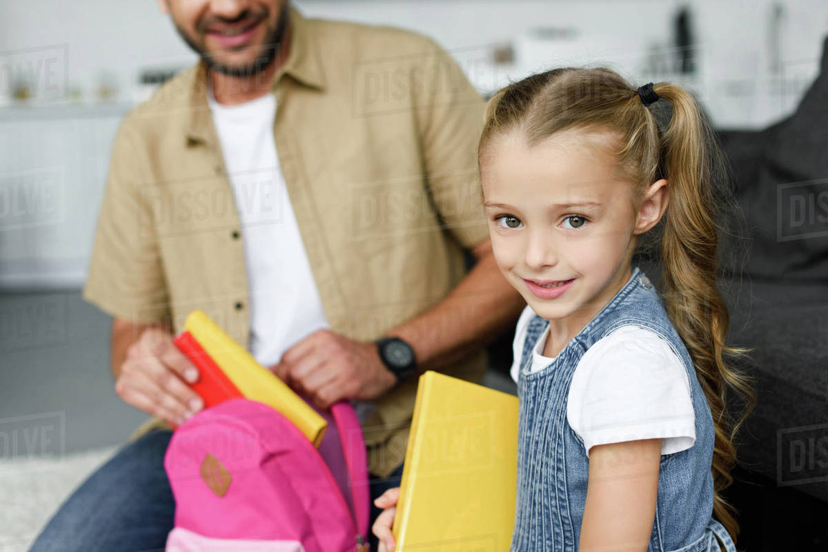 Partial view of daughter and father packing backpack for first day at ...