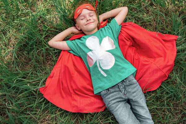 overhead view of kid with eyes closed in red superhero cape and mask ...