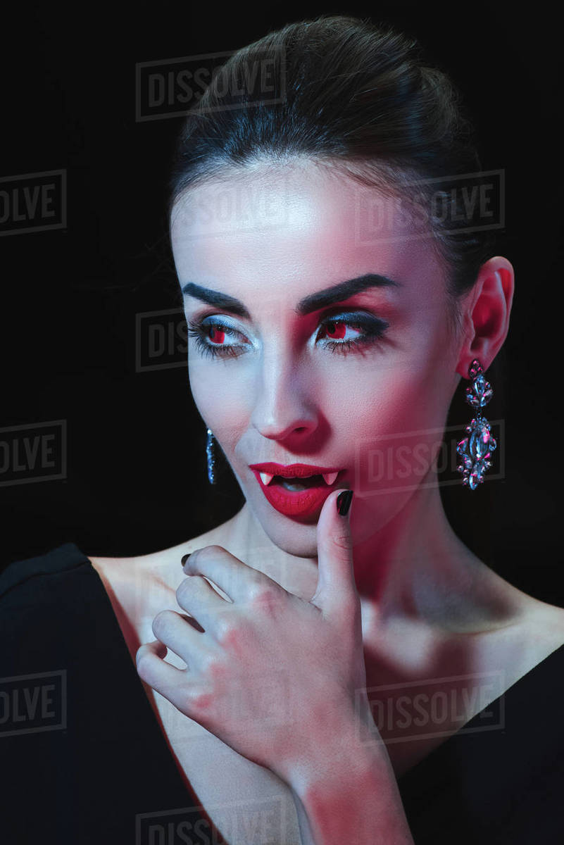 Attractive vampire touching her lips isolated on black - Royalty-free ...