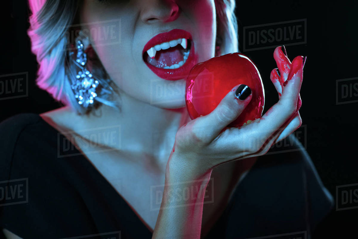 Cropped view of vampire biting red bloody apple isolated on black ...