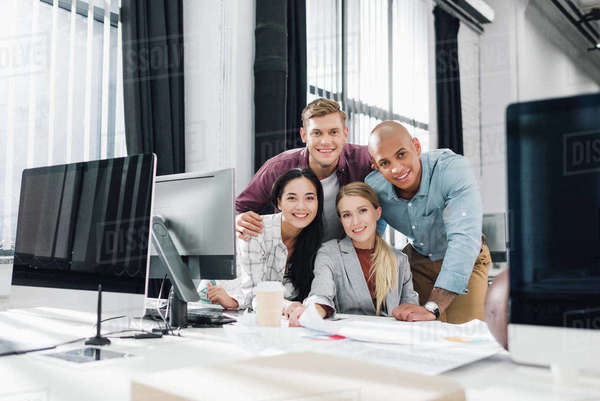 Happy young multiethnic colleagues smiling at camera in office - Stock ...
