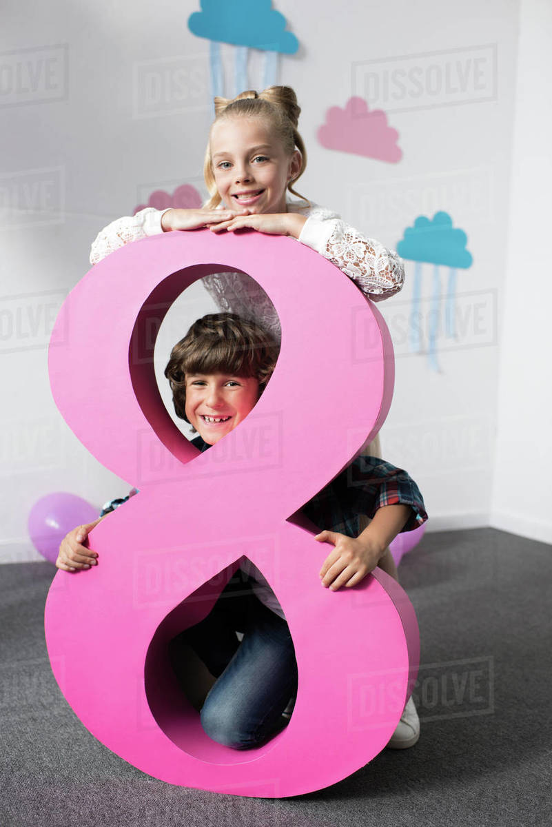adorable happy kids posing with decorative pink number eight at ...