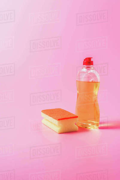 close up view of washing sponge and dishwashing liquid, pink background ...